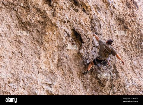 An Intrepid Climber Ascends A Steep And Craggy Rock Face Equipped With