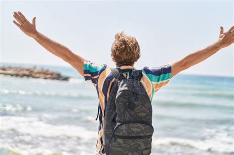 Young Man Tourist Wearing Backpack With Arms Open At Seaside Stock