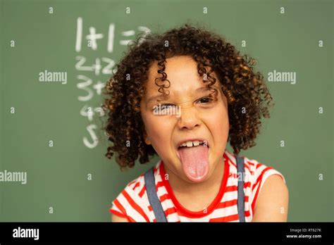 Schoolgirl Standing Against Green Board In A Classroom At School Stock