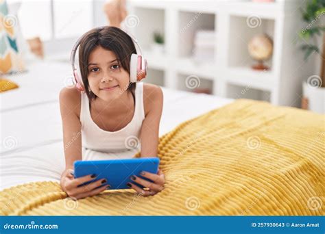 Adorable Hispanic Girl Watching Video On Touchpad Lying On Bed At
