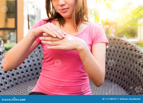 Young Woman Applying Body Lotion Or Cream On Hands While Sitting Stock