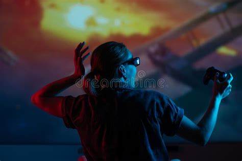 A Girl Gamer Plays Games With A Gamepad Joystick On A Large Screen