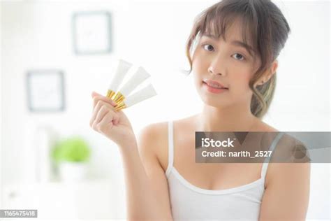 美麗的肖像年輕的亞洲婦女舉行和呈現奶油或化妝水產品 美容亞洲女孩顯示化妝品化妝和保濕的皮膚護理 健康護理和健康的概念 照片檔及更多 一個人