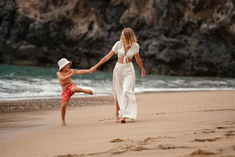 Feliz Joven Madre Y Niño Tomándose De La Mano Y Caminando Por La Playa