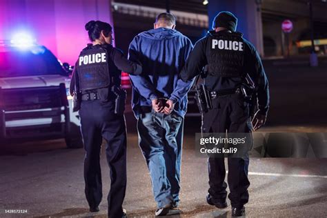 Handcuffed Suspect Being Arrested By Police At Night High Res Stock