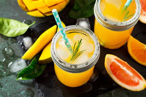 여름 칵테일 상쾌한 감귤 류와 망고 차가운 음료 또는 어두운 돌 배경에 얼음 음료를 만든다 채식 음식 신선한 비타민의 개념입니다