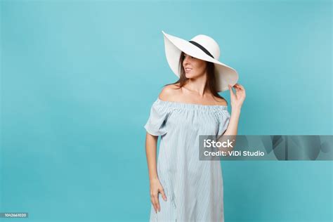 백색 여름 큰 넓은 가장자리 태양 모자 드레스에에서 아름 다운 젊은 여자 손 머리에 넣어 블루 파스텔 배경에 고립 된 복사