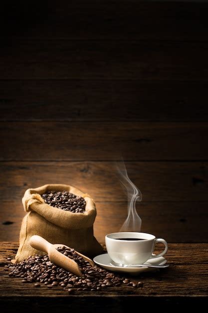 Tasse De Café Avec De La Fumée Et Des Grains De Café Sur Le Vieux Fond En Bois Photo Premium