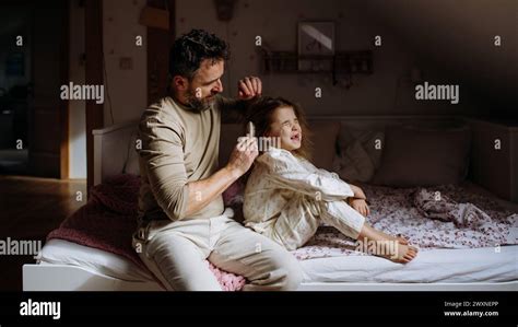 Father Combing And Braiding Daughter S Hair As Part Of Bedtime Routine