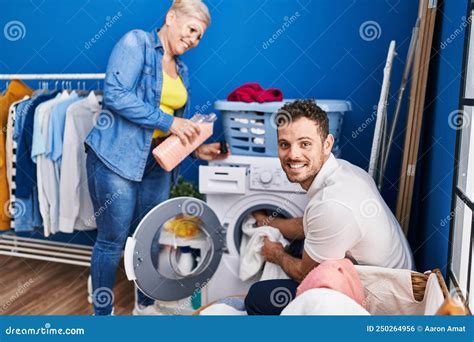 Mother And Son Washing Clothes Pouring Detergent On Washing Machine At