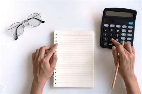 Premium Photo Woman Writing On Notebook While Using Calculator On Desk