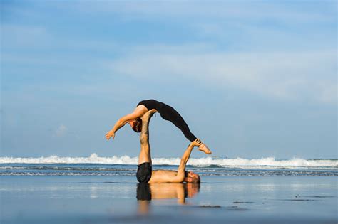 젊고 매력적이 고 아름 다운 곡예 사 커플을 연습 Acroyoga 운동 집중 유지 균형 휴식과 명상 개념과 건강 한 라이프 스타일에 해변에서 요가를 연습 2명에 대한 스톡