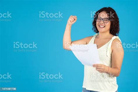 안경을 쓴 여자 몇 가지 문서를 들고 카메라를 보고 매우 행복하게 웃으며 성공의 표시로 팔을 들어 올리는 여성 라틴 아메리카