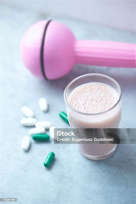 우유와 라즈베리가 포함 된 단백질 셰이크 유리 Bcaa 아미노산 L카 르 니 틴 캡슐 및 핑크 아령 배경 스포츠 영양 돌 나무