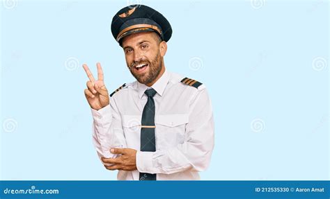 Handsome Man With Beard Wearing Airplane Pilot Uniform Smiling With