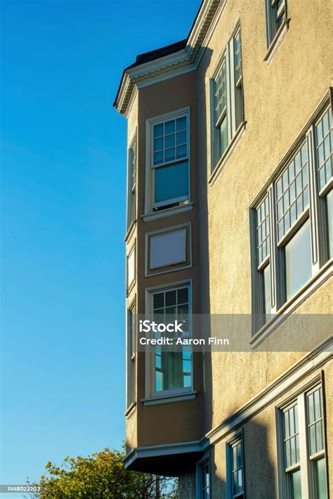 베이지 또는 크림색의 치장 벽토 외관 이른 아침 그늘과 푸른 하늘에 보이는 창문과 어두운 액센트 페인트 개발에 대한 스톡 사진