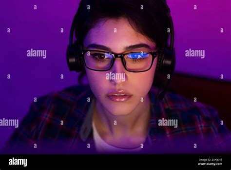 Female Programmer Working On Laptop Late At Night Room Illuminated By Neon Light Stock Photo