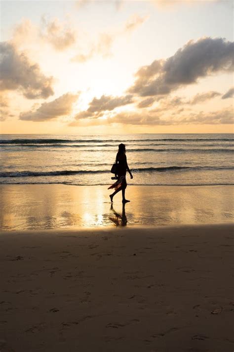 Toma Vertical De La Silueta De Una Mujer Caminando Por La Playa Al