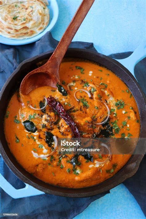 붉은 양파 슬라이스와 겨자 씨앗 라샤 파라타 와 카레 소스에 닭 가슴살 고기의 큰 덩어리로 가득 청록색 요리 팬에 제공되는 인도 버터 치킨 티카 카레의 이미지 0명에 대한