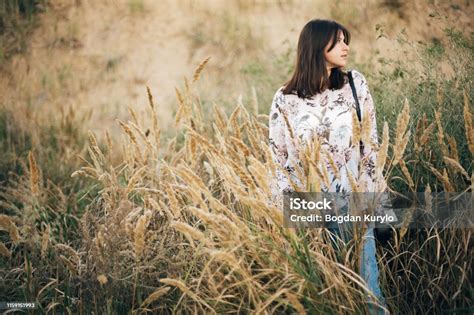 야생화에서 포즈를 취하는 세련된 힙스터 소녀 해변의 긴 허브 및 바다 근처 절벽 여름 방학 잔디 사이에서 휴식을 취하는 행복한
