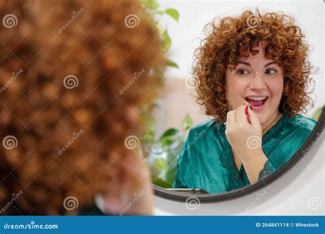 Chubby Female With Curly Ginger Hair Applying Makeup In A Bathroom