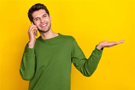 귀여운 재미 젊은 남자의 사진 녹색 스웨터를 착용 팔 빈 공간 고립 된 노란색 배경 들고 현대 장치 이야기 손에 대한 스톡 사진