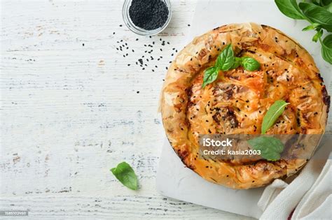 오래된 흰색 나무 테이블 배경에 부드러운 페타 치즈와 시금치를 곁들인 맛있는 파이 스파나코피타 전통적인 그리스 나선형 필로