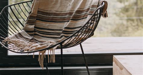 아늑한 담요와 금속 장작이 있는 현대적인 검은색 의자는 산의 전망을 감상할 수 있는 큰 창문을 배경으로 서 있습니다 추운 계절에 오두막에서 아늑하고 따뜻하고 차분한 순간