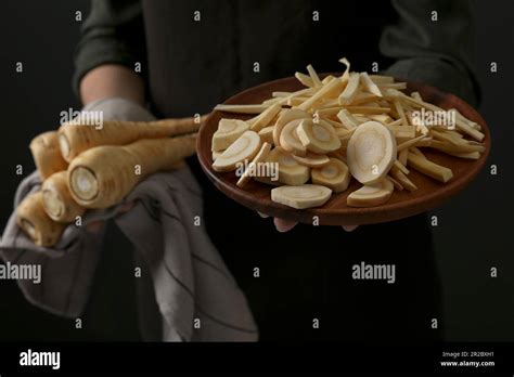 Woman Holding Whole And Cut Parsnips On Black Background Closeup Stock