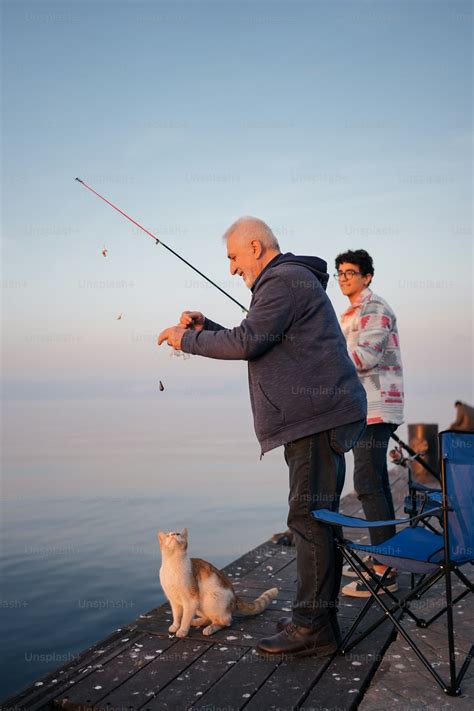 고양이와 함께 부두에 서있는 남자와 여자 사진 Unsplash의 낚시 이미지
