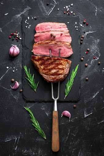 검은 돌 배경에 향신료와 허브와 희귀 구운 Ribeye 쇠고기 스테이크 중간 상단 보기 플랫 레이 복사 공간 검은색에 대한 스톡