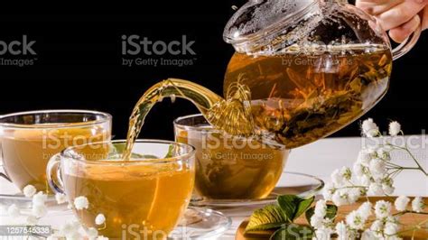 찻주전자에서 양조한 녹차를 머그잔에 붓습니다 차 파티 다도 선 스타일의 전통 녹차 한 잔과 주전자 과일 슬라이스와 꽃 차 다도 전통 음료 증기에 대한 스톡 사진 및 기타