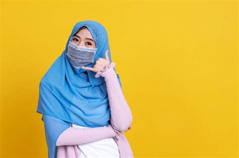 코로나바이러스 Covid19 전염병을 보호하고 왼손으로 부름 표지판을 만드는 것을 보여주는 의료 용 마스크를 쓴 아시아 무슬림