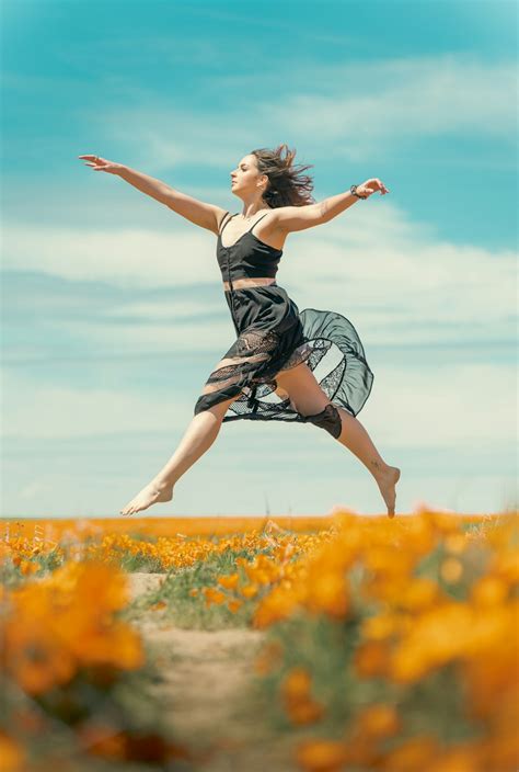 A Woman Is Jumping In The Air In A Field Of Flowers Photo Free