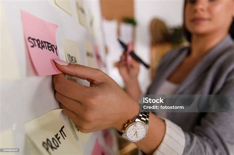 Businesswoman Putting A Sticky Note With The Word Strategy Written On