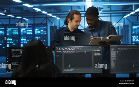 Inspector Overseeing Server Room Reading Paperwork And Evaluating Work Done By Multiracial Team