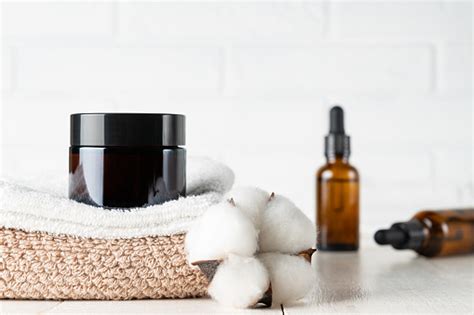 노화 방지 콜라겐 얼굴 세럼을 어두운 유리 병에 넣고 복사 공간이있는 흰색 배경에 얼굴 크림을 바르십시오 천연 유기농 화장품
