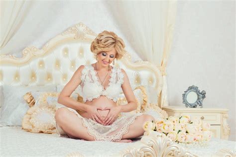 Beautiful Pregnant Brunette Sitting On A Bed In The Lotus Position