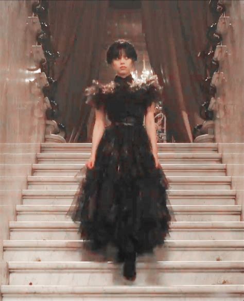 A Woman In A Black Dress Standing On Some Stairs