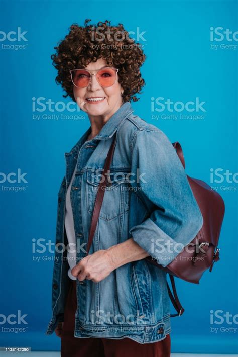 현대 안경 파란색 배경에 카메라에 대 한 포즈와 함께 웃는 노인 여자 가방에 대한 스톡 사진 및 기타 이미지 가방 갈색