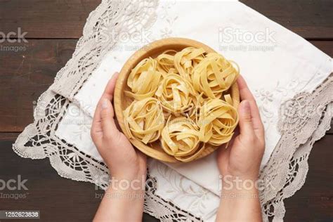 나무 테이블에 원시 페투치네 파스타와 나무 접시를 들고 여성의 손 Sable Color에 대한 스톡 사진 및 기타 이미지