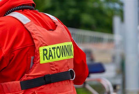 빨간 제복을 입고 Ratownik이라고 적힌 눈에 잘 띄는 조끼를 입은 인명 구조원 뒤에서 클로즈업 보기 안전 수상 구조 및 응급 서비스와 관련된 테마에 적합 폴란드에 대한