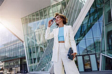 하얀 양복을 입고 미소 짓는 젊은 사업가가 고층 빌딩 도시 풍경 배경에 서 있습니다 30 34세에 대한 스톡 사진 및 기타 이미지 30 34세 갈색 머리 거리