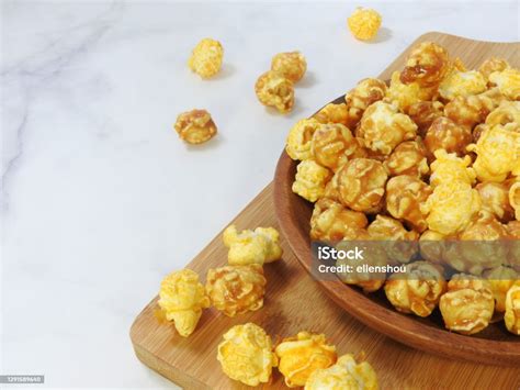 회색 대리석 배경에 고립 된 둥근 나무 접시에서 맛있는 팝콘의 높은 각도보기 버터가 많은 캐러멜 옥수수와 풍부한 체다 치즈