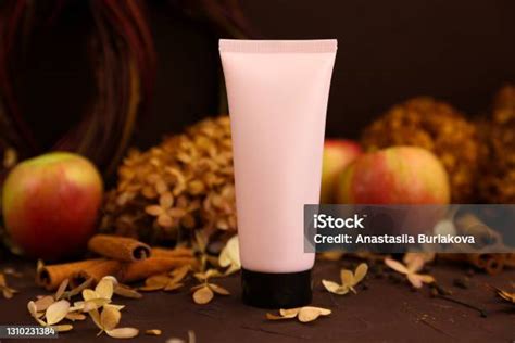 검은 모자 계피 사과 다크 브라운 배경에 드라이 수국 꽃핑크 스퀴즈 병 화장품 튜브 상단 보기 브랜드가 없는 로션 발삼 핸드 크림 치약 모형 템플릿 0명에 대한 스톡 사진