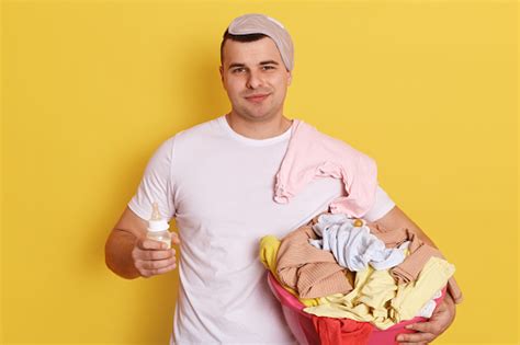 집에서 세탁을하고 신생아를 돌보고 린넨으로 수유병과 분지를 들고 차분한 표정으로 카메라를 직접 바라보며 해야 할 일이 많이