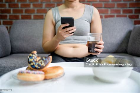과식과 폭식 개념 건강에 해로운 음식을 먹는 소파에 앉아 있는 뚱뚱한 여자 30 34세에 대한 스톡 사진 및 기타 이미지