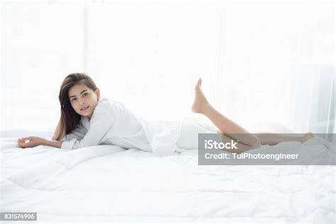 아름 다운 젊은 웃는 여자 아시아 여 자가 침대에 앉아서 그녀의 침대에서 완전히 깨어난 후 침실에서 아침에 스트레칭 휴식 가정의
