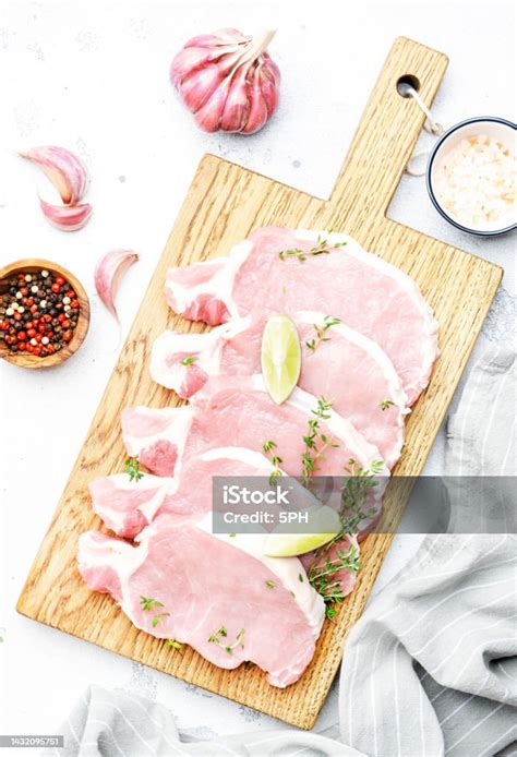 생 돼지 고기 볶음 마늘 백리향 및 후추로 요리하기 위해 준비된 커팅 보드의 고기 하얀 부엌 테이블 평면도 0명에 대한 스톡