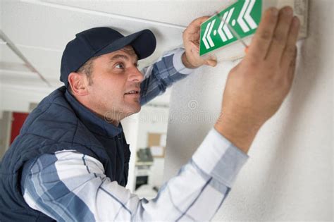 Man Working On Illuminated Exit Sign To Wall Stock Photo Image Of Security Icon